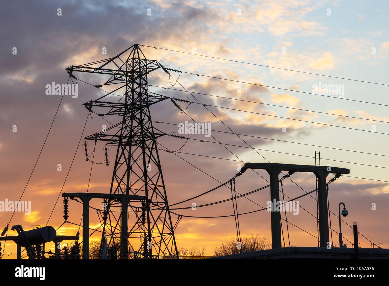 Silhouette of pylon and substation against a warm sunset sky. High ...
