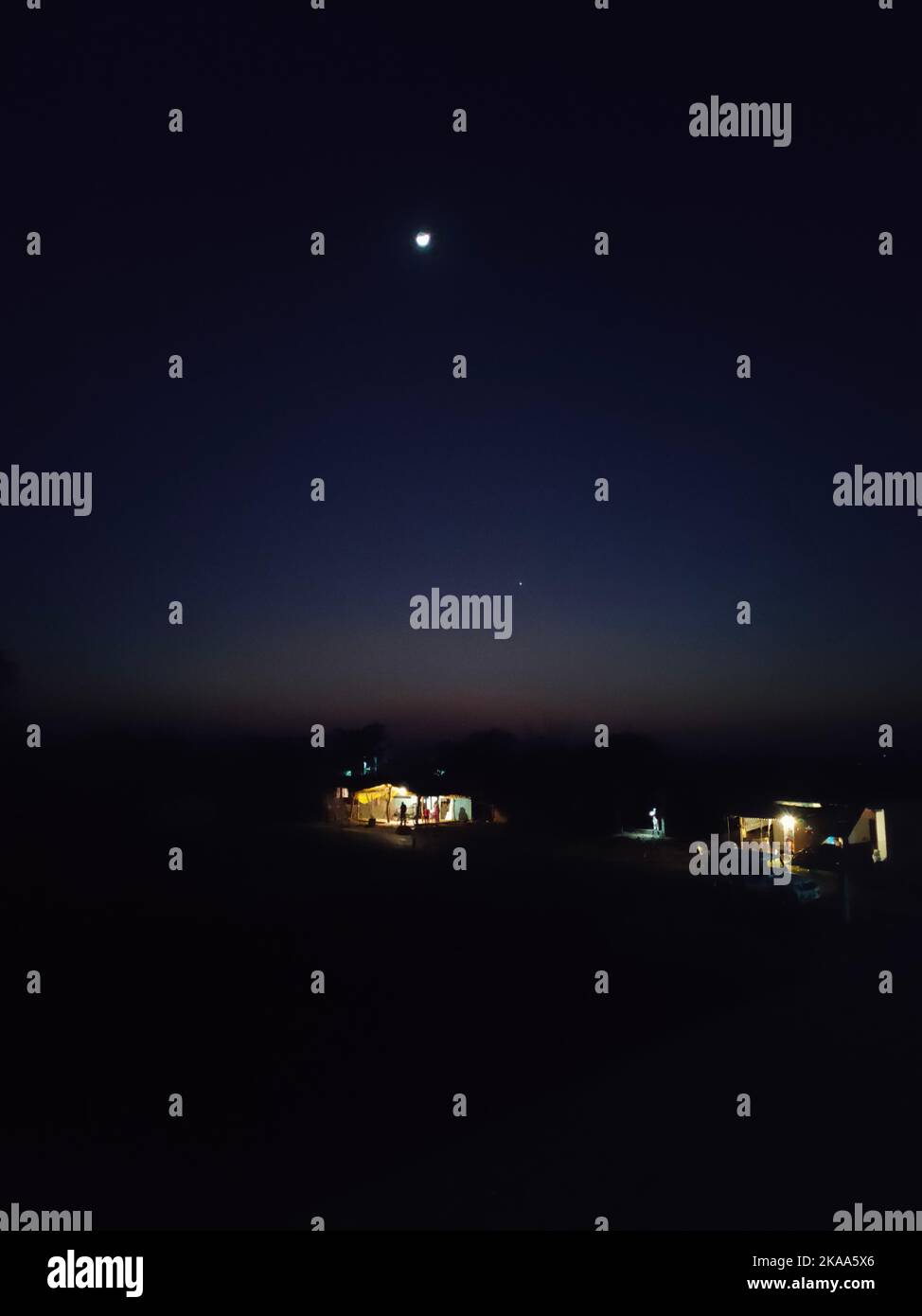 A night view of two illuminated houses under the moonlight in Mahkhor ...