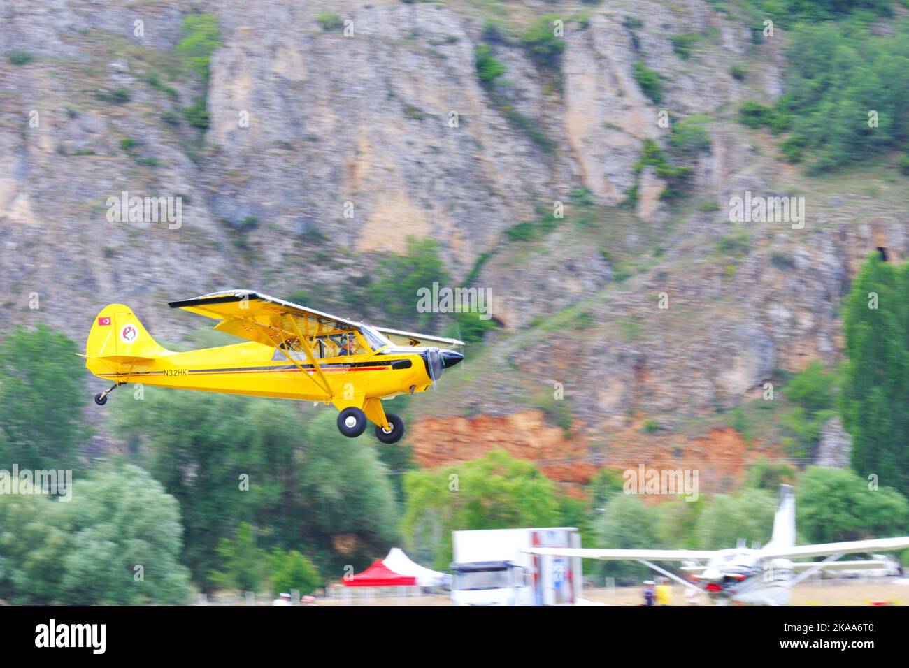 Yellow single engine plane approaching to the ground with rocks at the ...