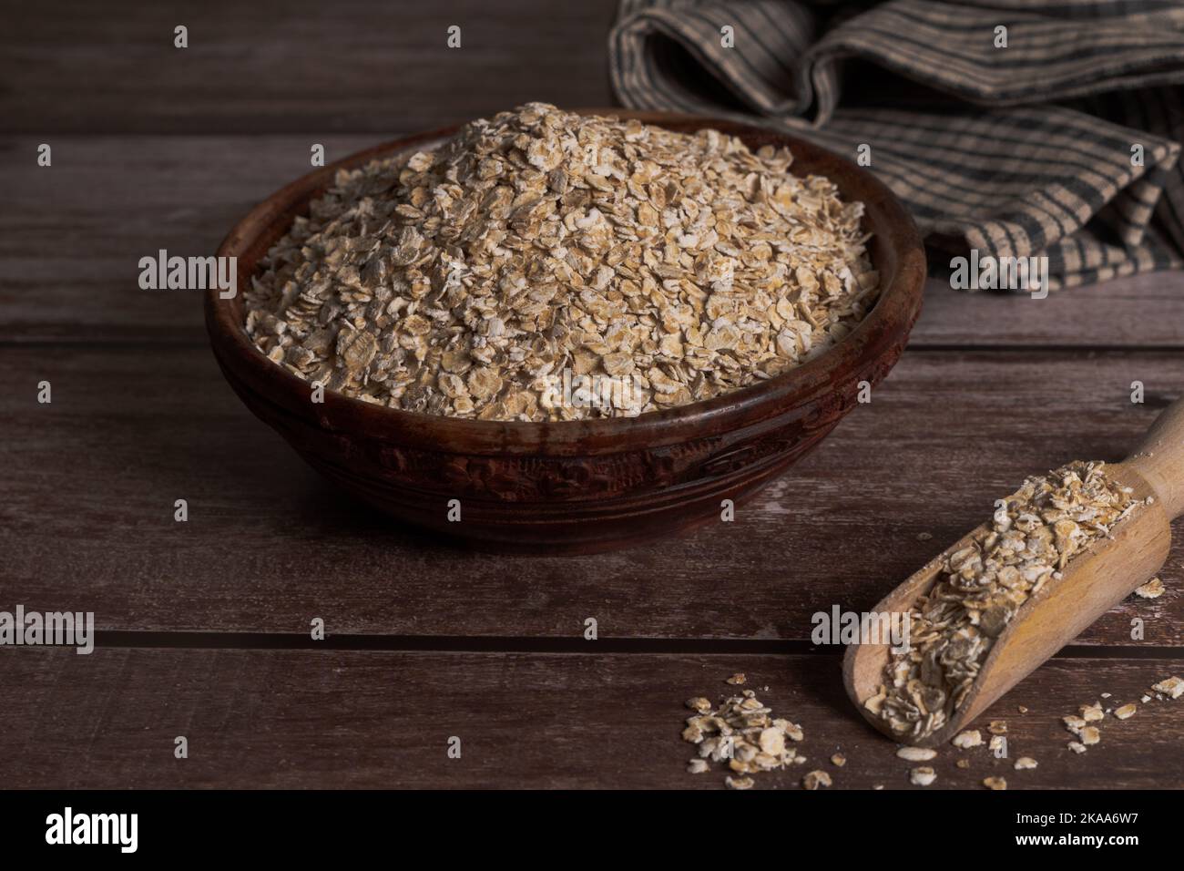 oat flakes in a wooden bowl with a kitchen towel on a wooden table and ...