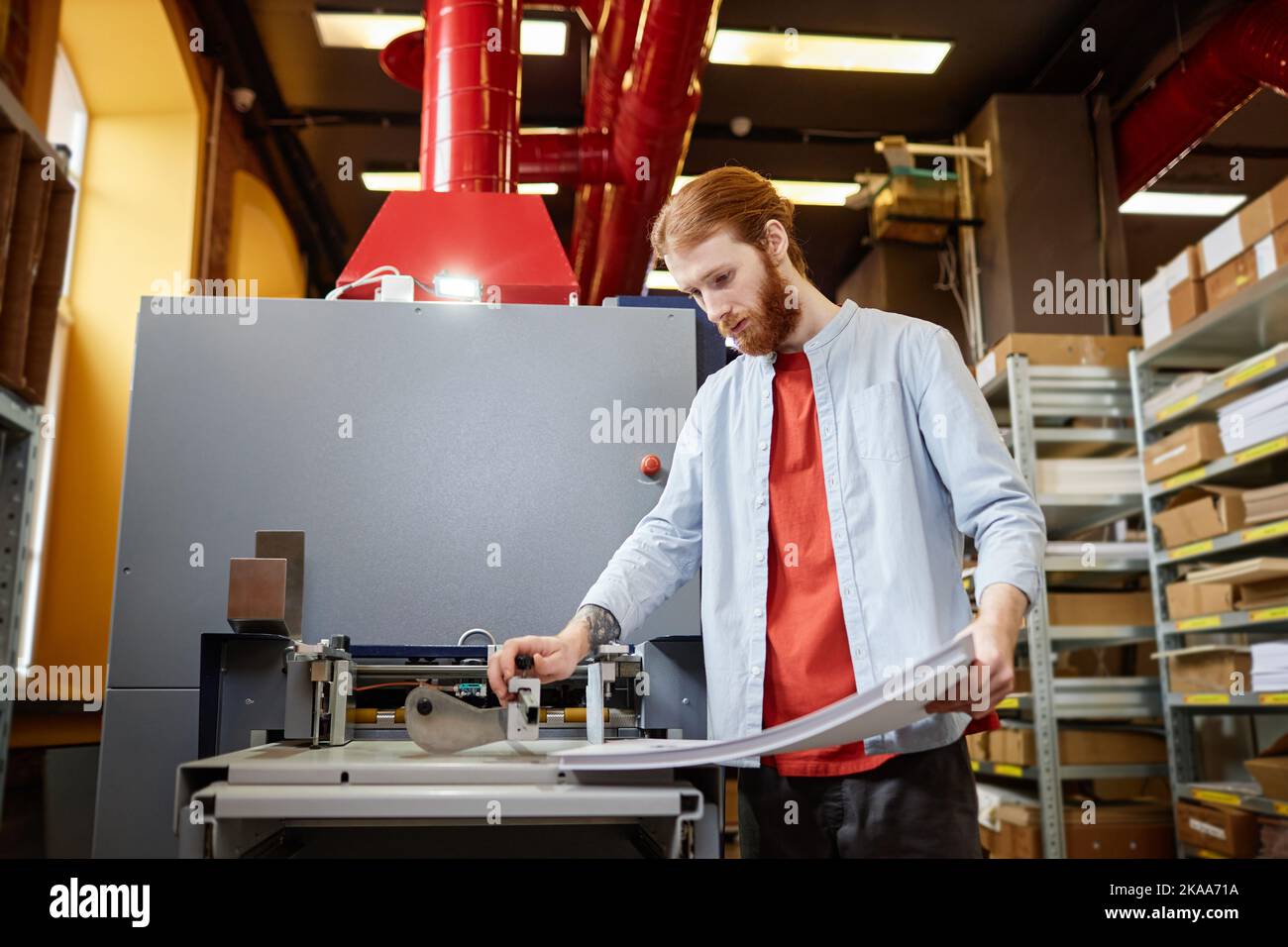 Side view portrait of bearded man putting paper in industrial printing ...
