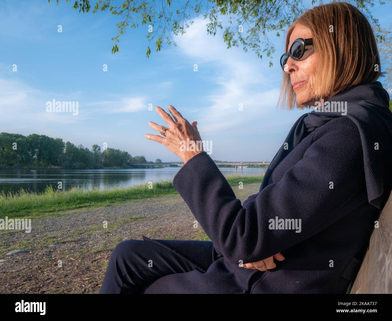 adult mature elegant caucasian woman sitting on a park bench with legs ...