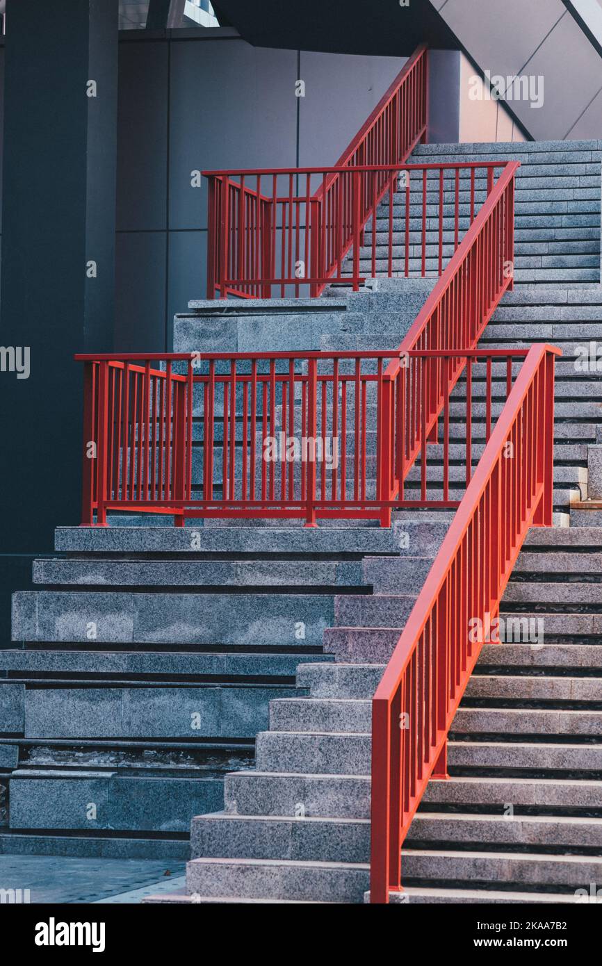 A vertical shot of a building with a staircase and red-painted railings ...