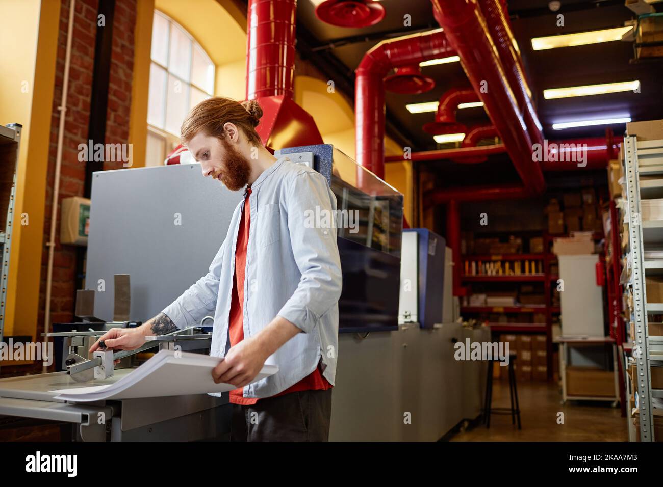 Side view portrait of bearded young man operating industrial printing ...