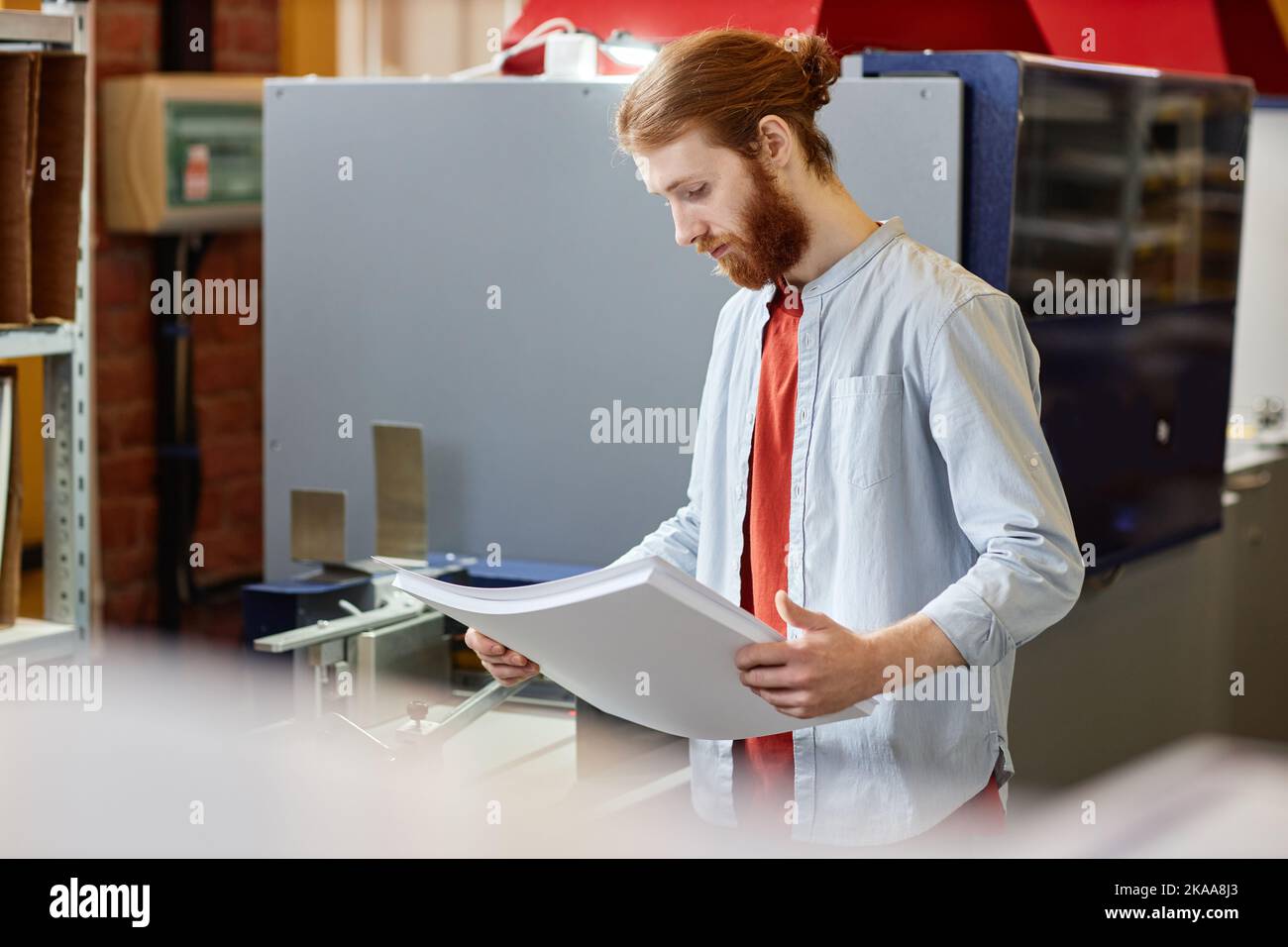 Side view portrait of smiling young man by industrial printing machine ...
