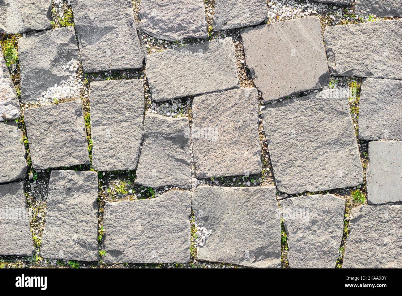 Texture of masonry roads made of asymmetrical stones with grass between ...