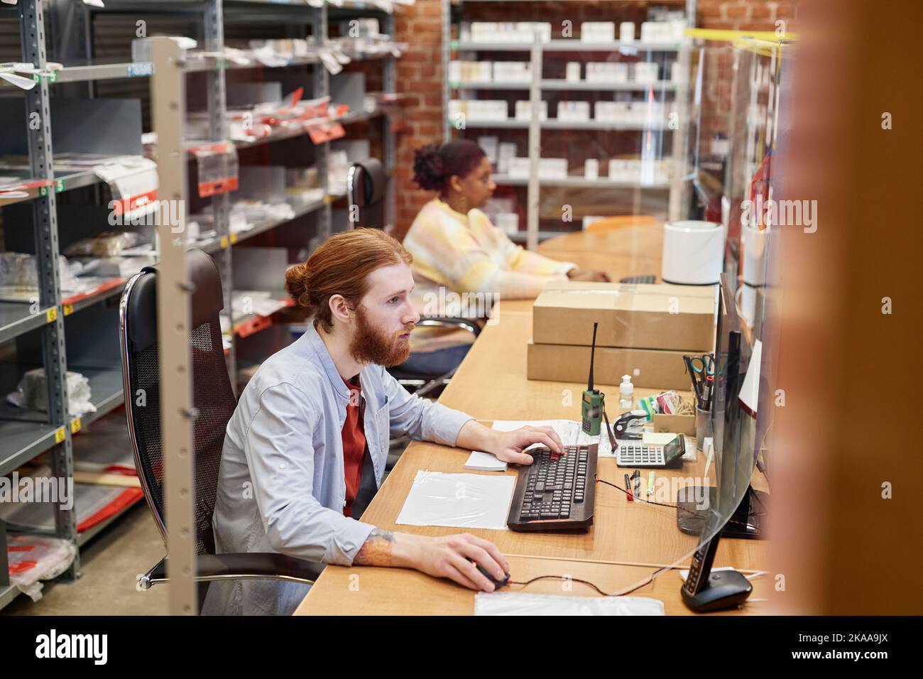 Side view portrait of workers using computers at printing shop or ...