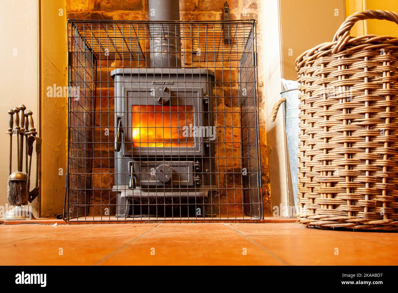 Flaming log wood burning stove behind a mesh fire guard in one of the ...