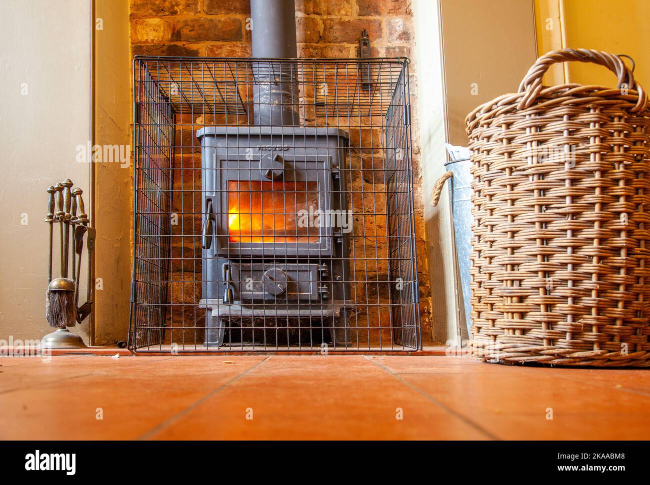Flaming log wood burning stove behind a mesh fire guard in one of the ...