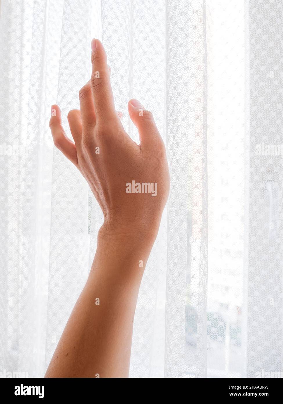 Graceful woman hand on tulle curtains background. Sun lights through ...