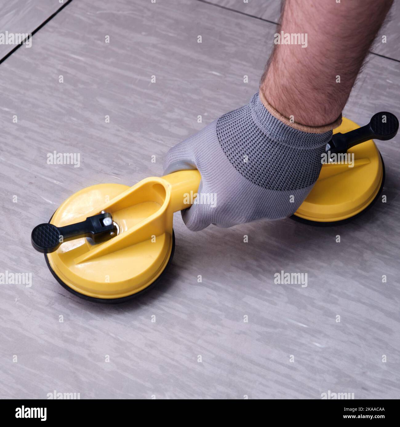 Worker hands with vacuum suction cups for lifting floor panels. A man ...