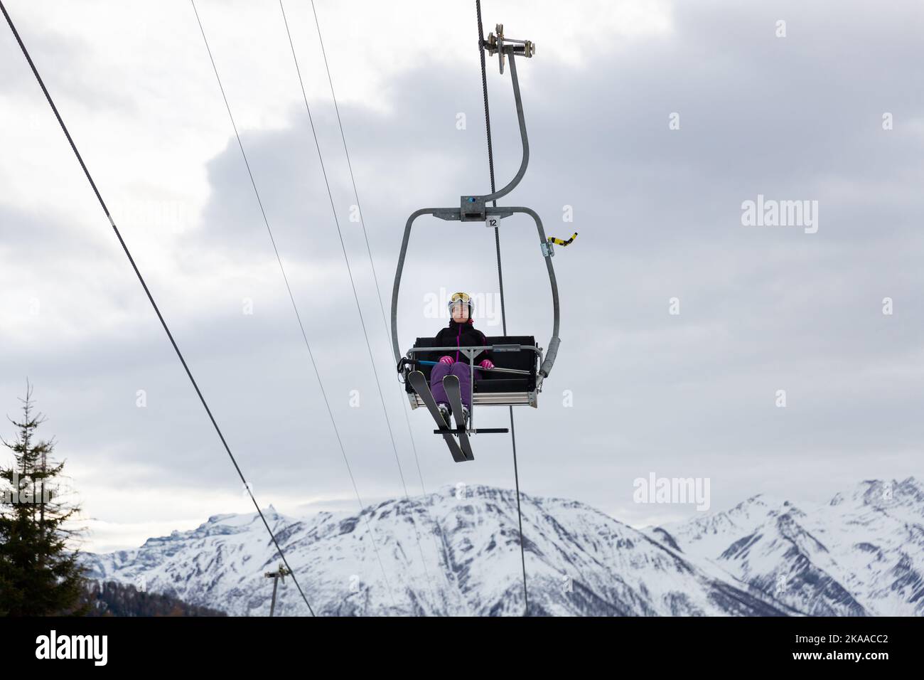 Woman skier riding on chairlift on background of snowy mountains Stock ...