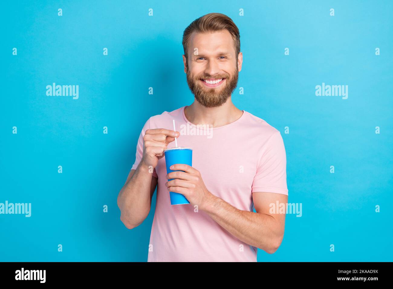 Photo of adorable cheerful guy dressed pink t-shirt smiling drinking ...