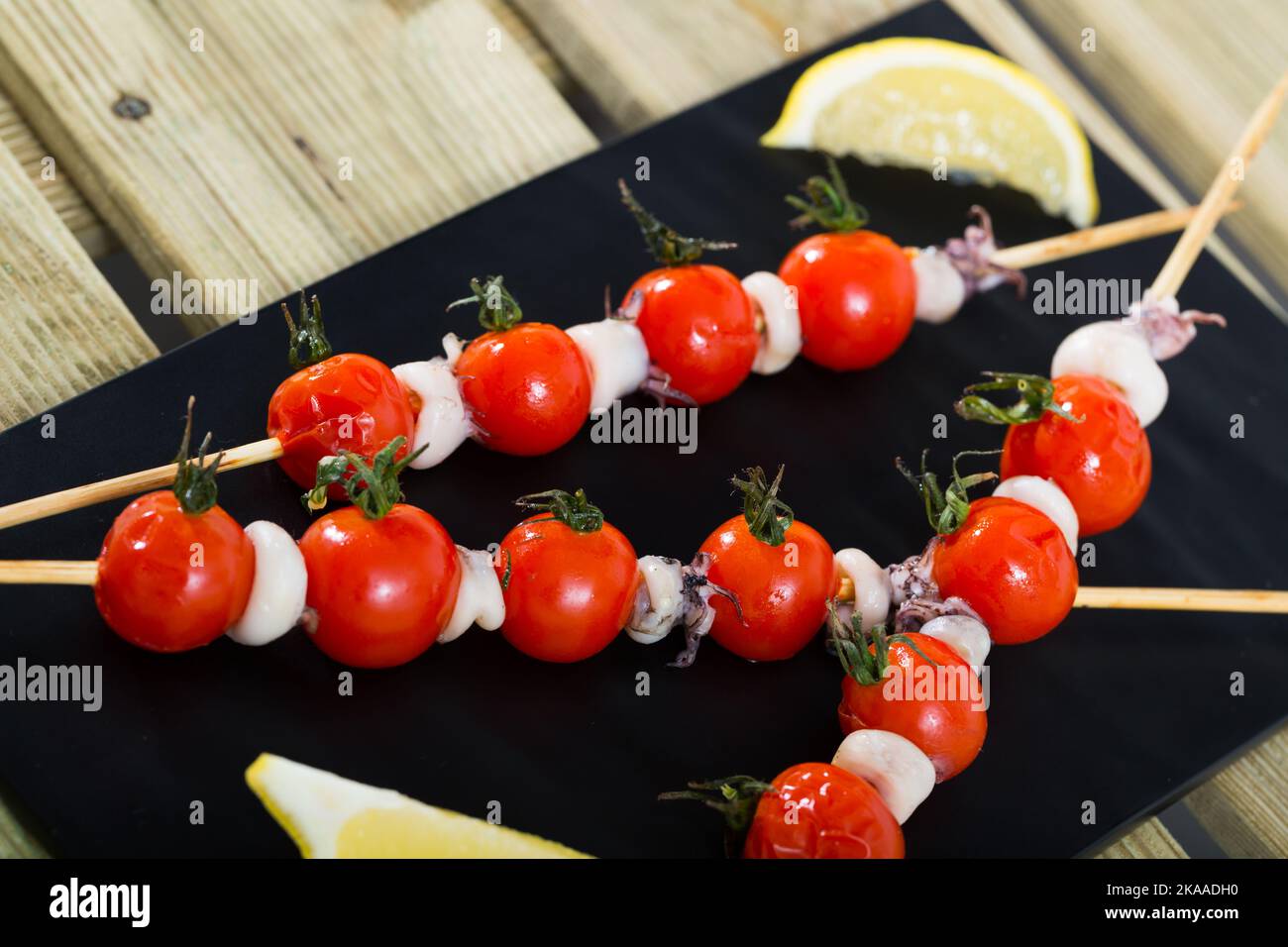 Grilled mini-squid with cherry tomatoes Stock Photo - Alamy