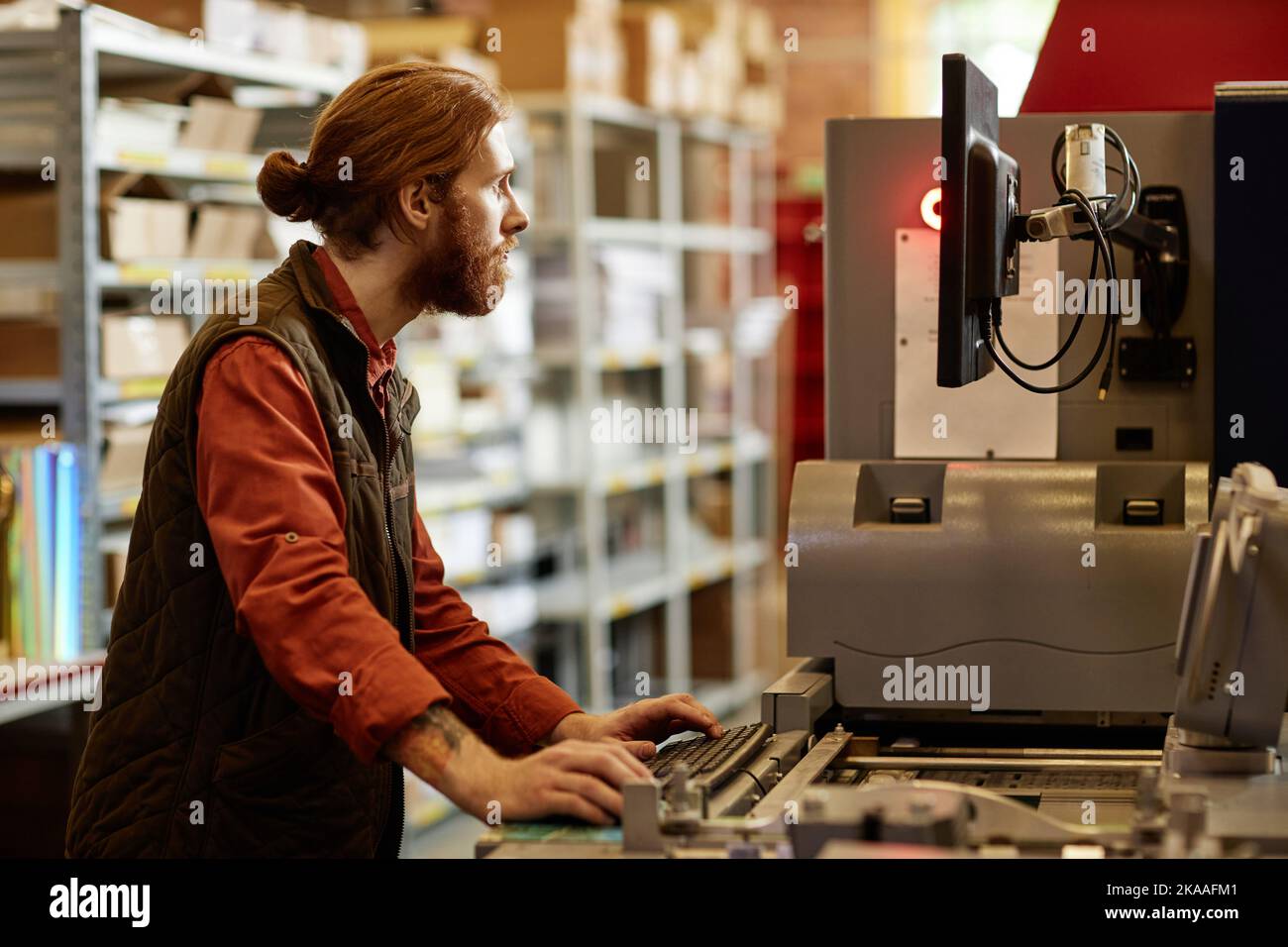 Side view portrait of male worker operating printing machine at print ...