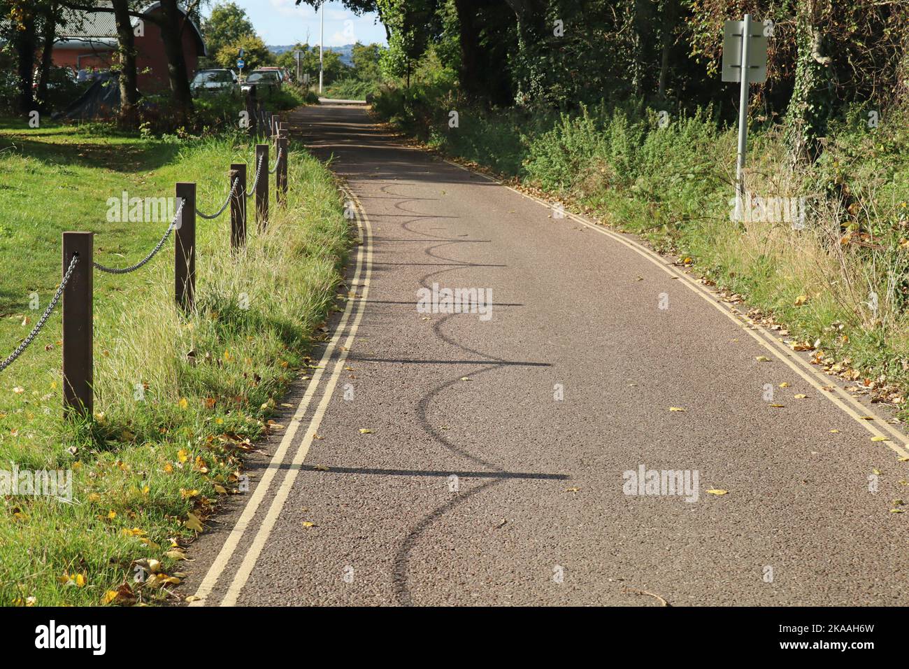 A narrow lane with double yellow lines denoting no parking. The road is ...