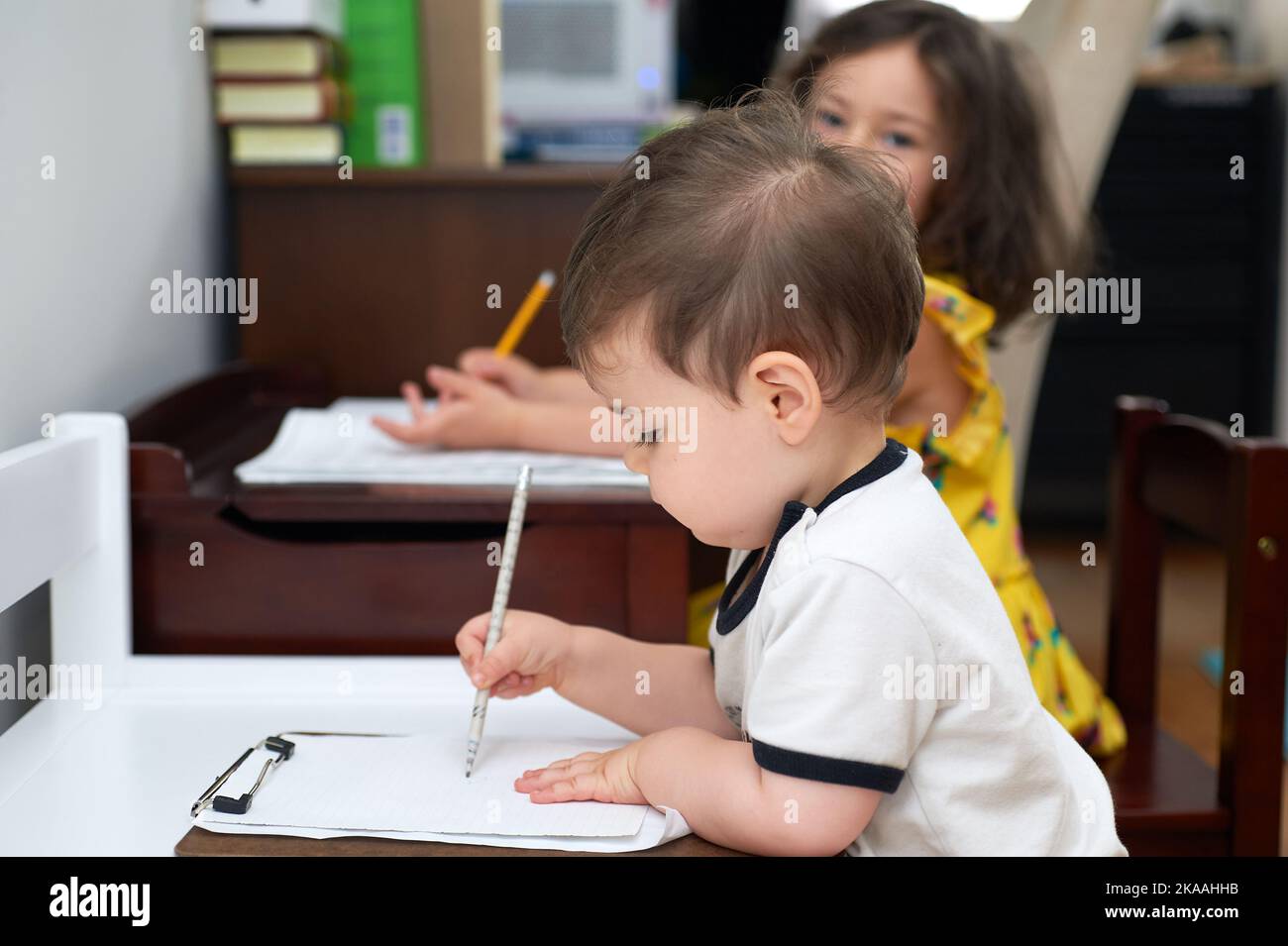 Little toddler copying his sister doing her homework Stock Photo - Alamy