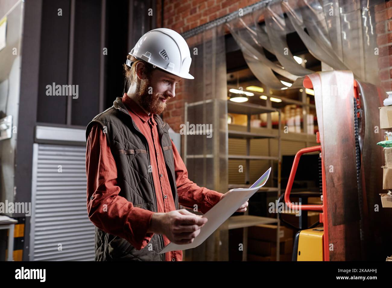 Side view portrait of bearded worker wearing hardhatat factory and ...