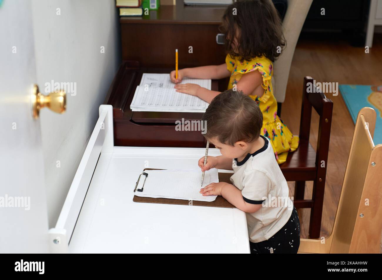 Little toddler copying his sister doing her homework Stock Photo - Alamy