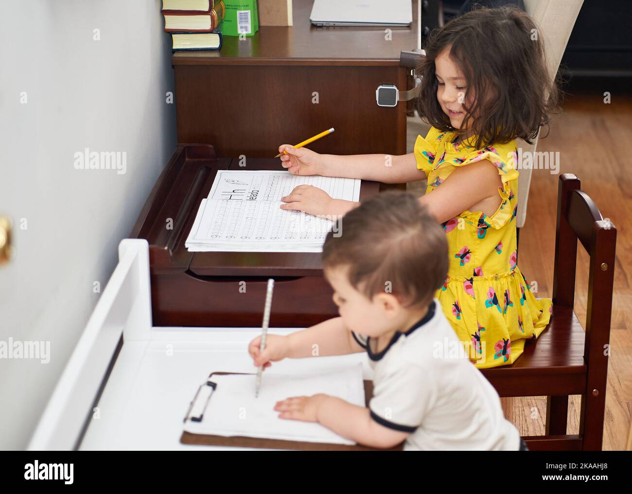 Little toddler copying his sister doing her homework Stock Photo - Alamy