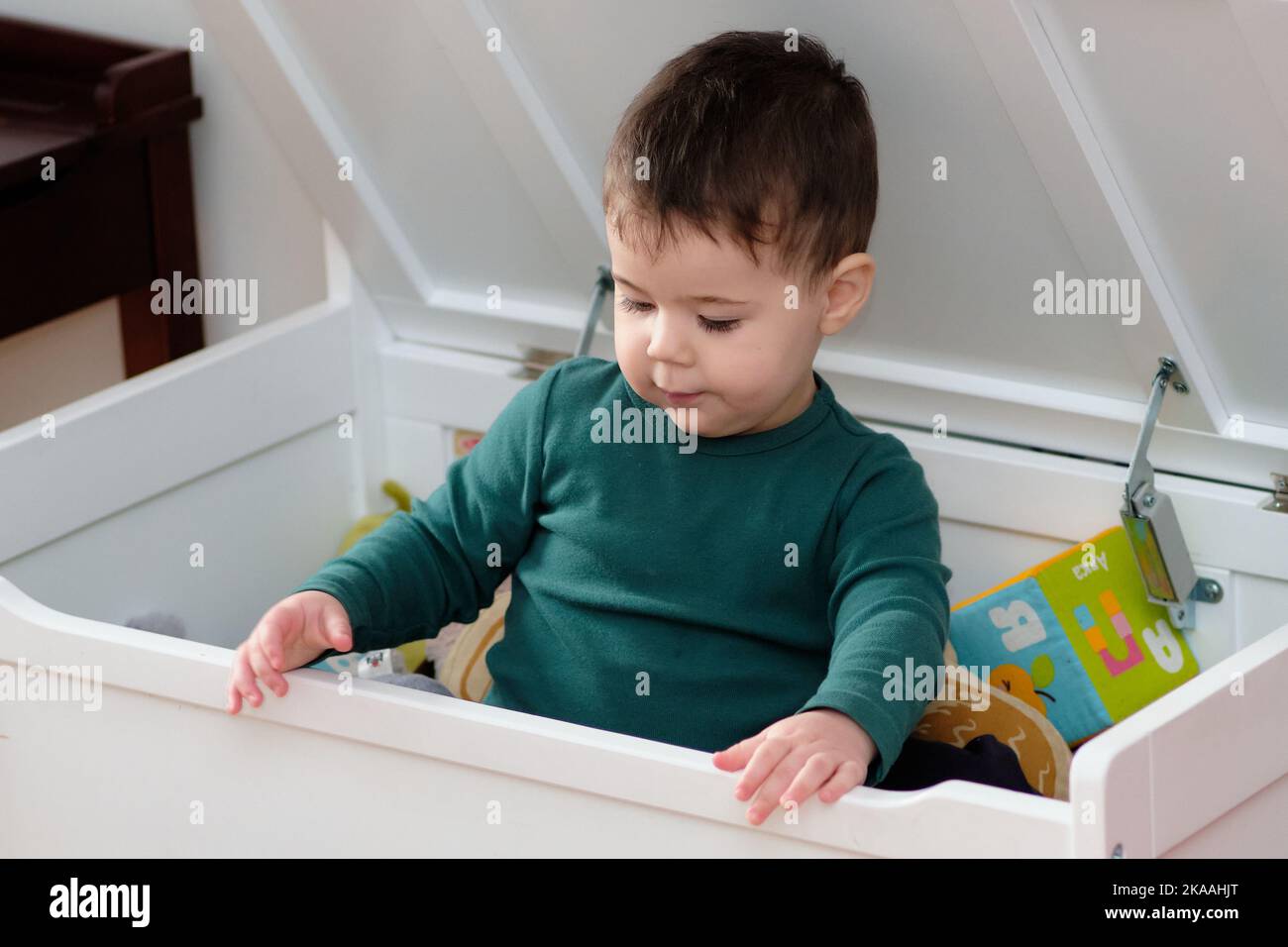 Little toddler playing with his plush toys inside the toy box Stock ...