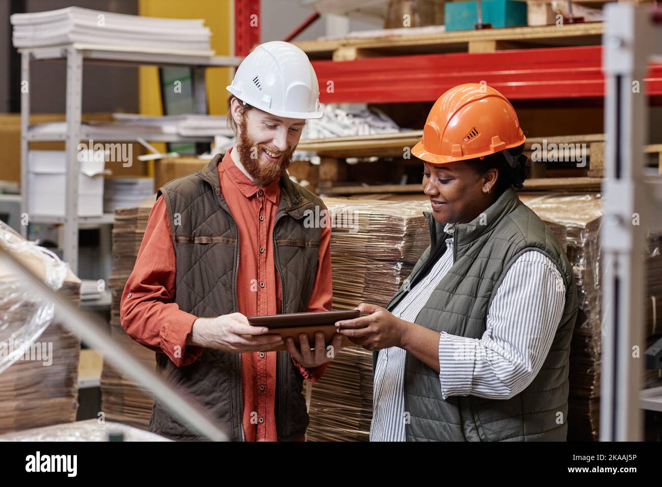 Waist up portrait of two workers wearing hardhats in factory workshop ...