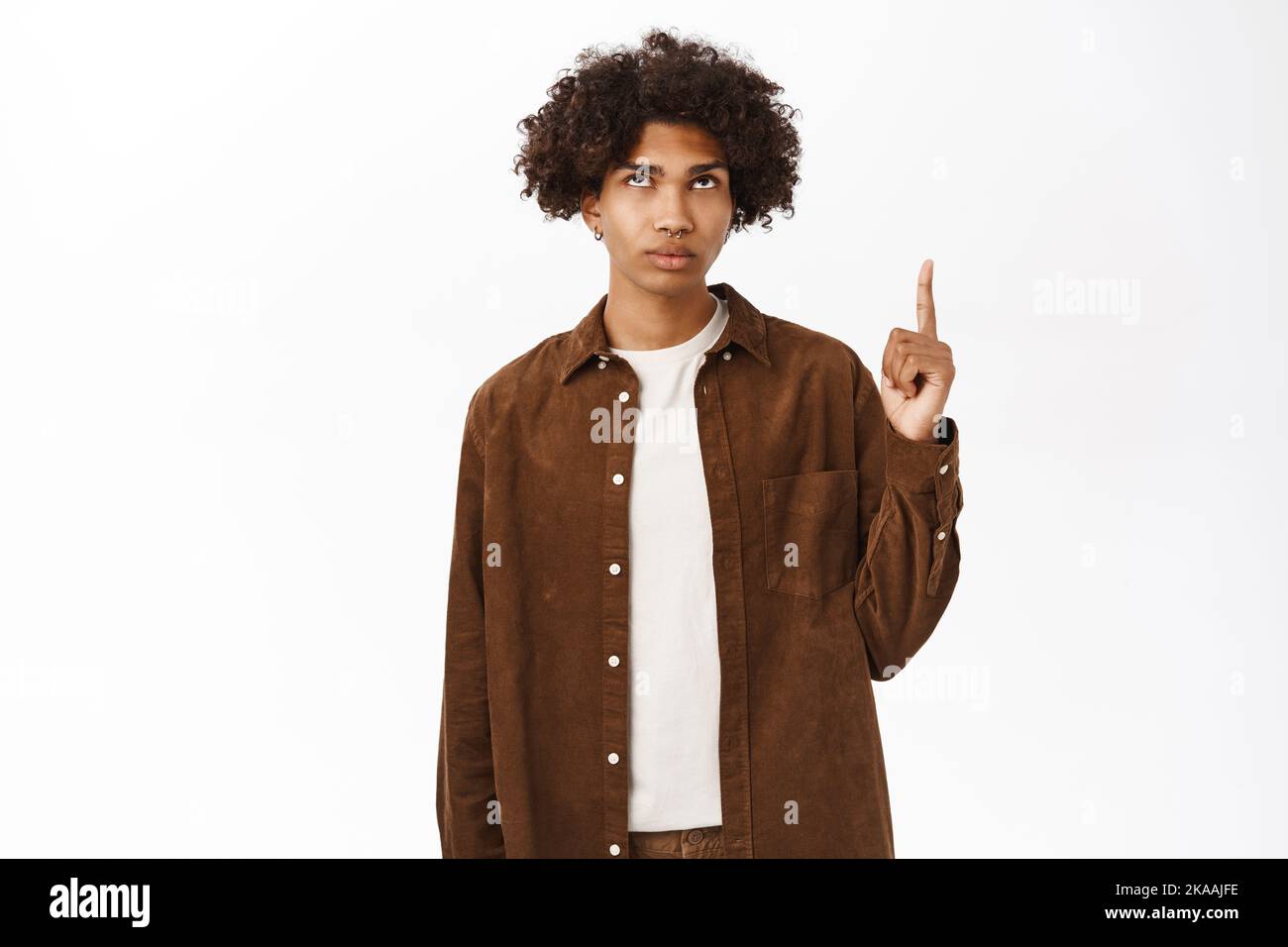 Portrait of young man with tired face pointing, looking up, showing ...