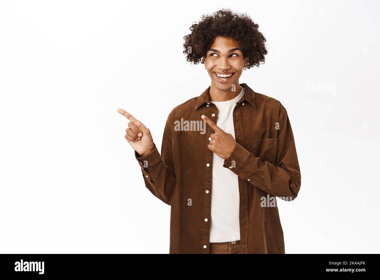 Portrait of handsome young man pointing left, showing advertisement ...