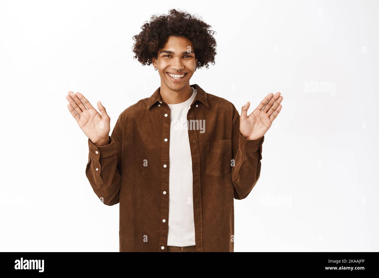Portrait of friendly gen-z guy says hello, waves hand and smiles happy ...