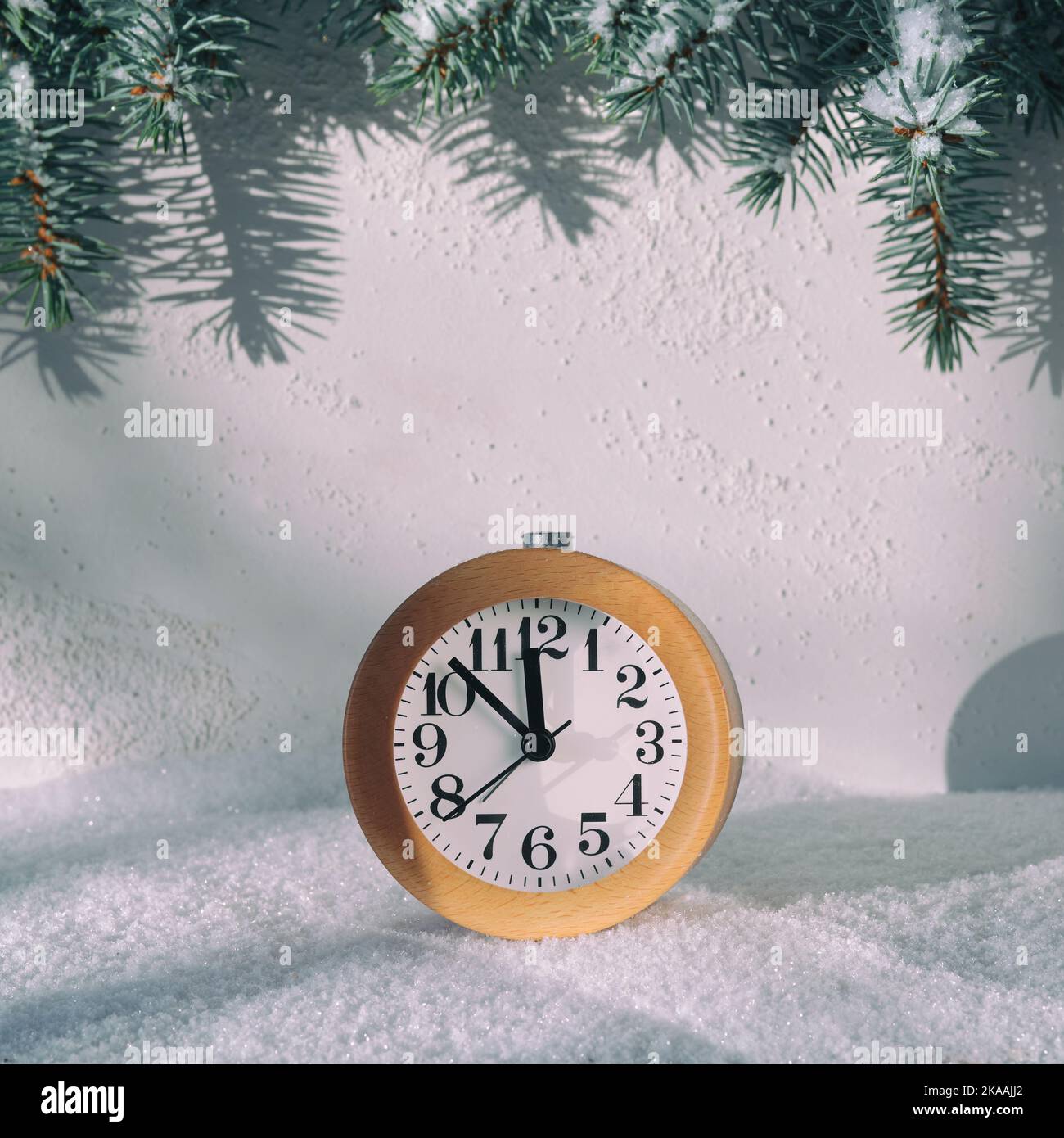 Wood alarm clock with fir twigs and snow. Time ten to midnight. Off ...