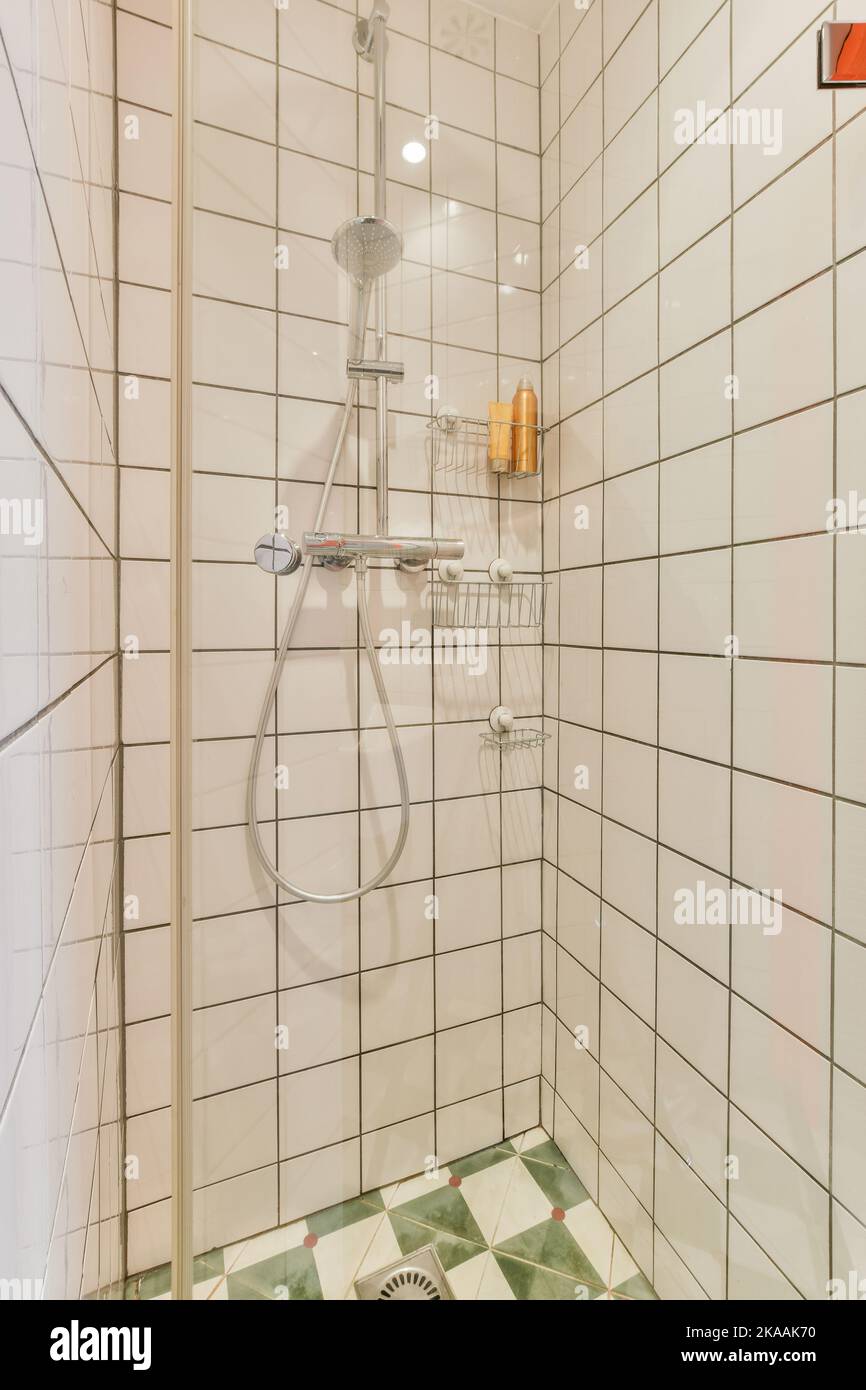 Shower faucets attached to tiled wall near glass partition in washroom ...