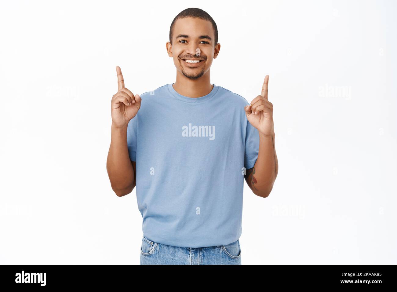 Handsome smiling man pointing fingers up, shows promo offer ...