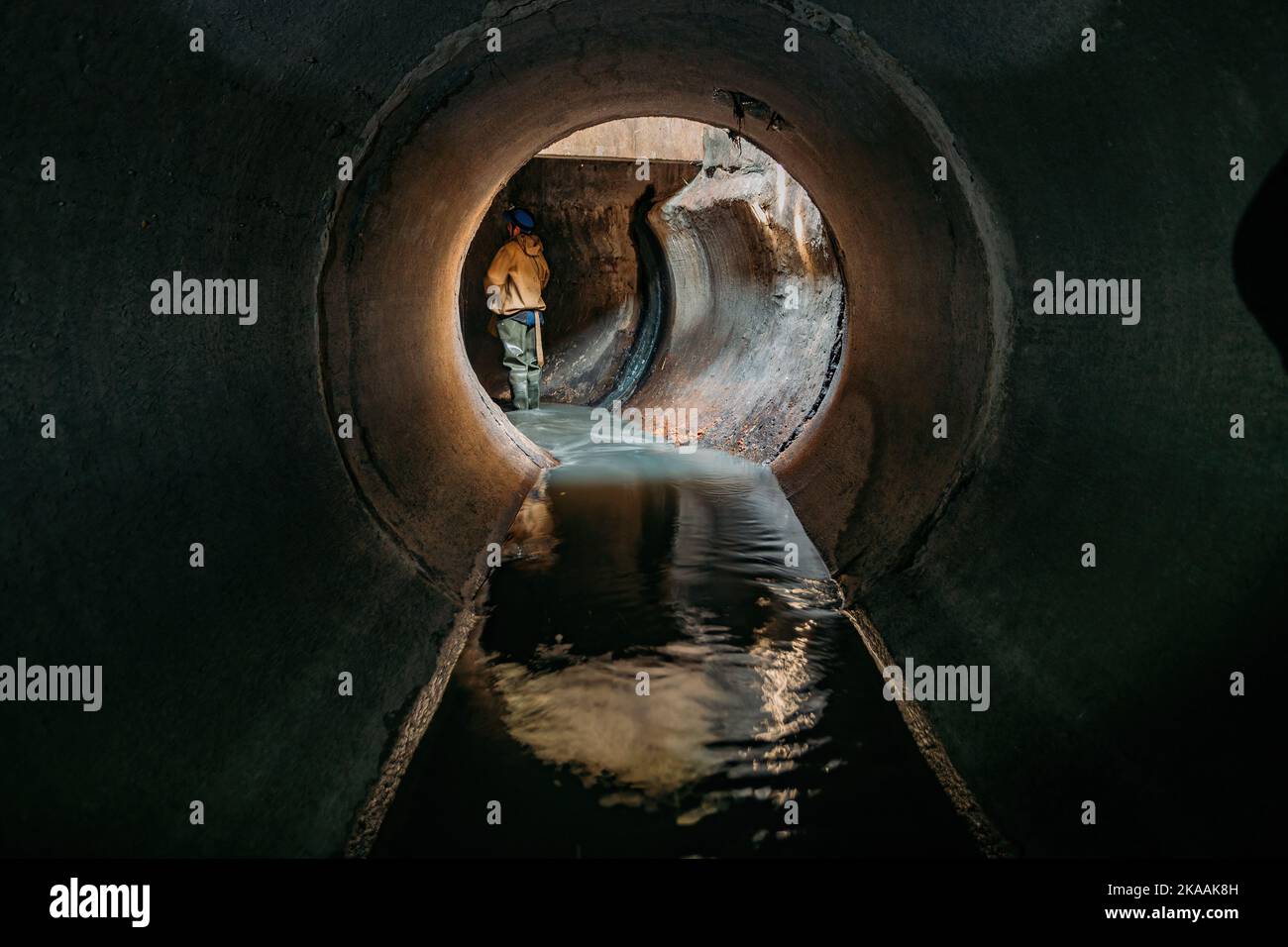 Sewer tunnel worker examines sewer system damage and wastewater leakage ...