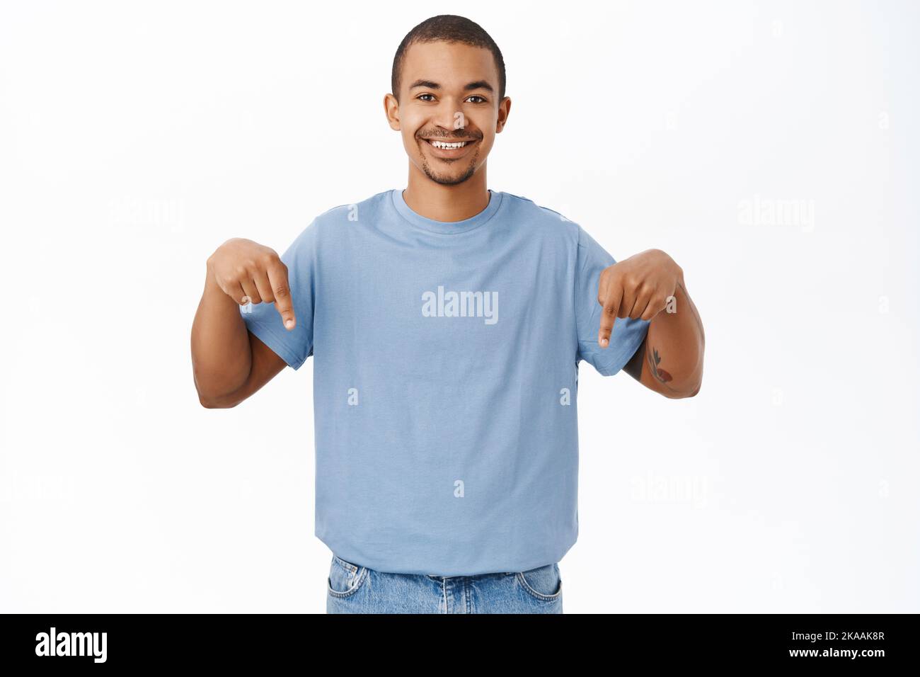 Smiling handsome man pointing fingers down, showing advertisement ...