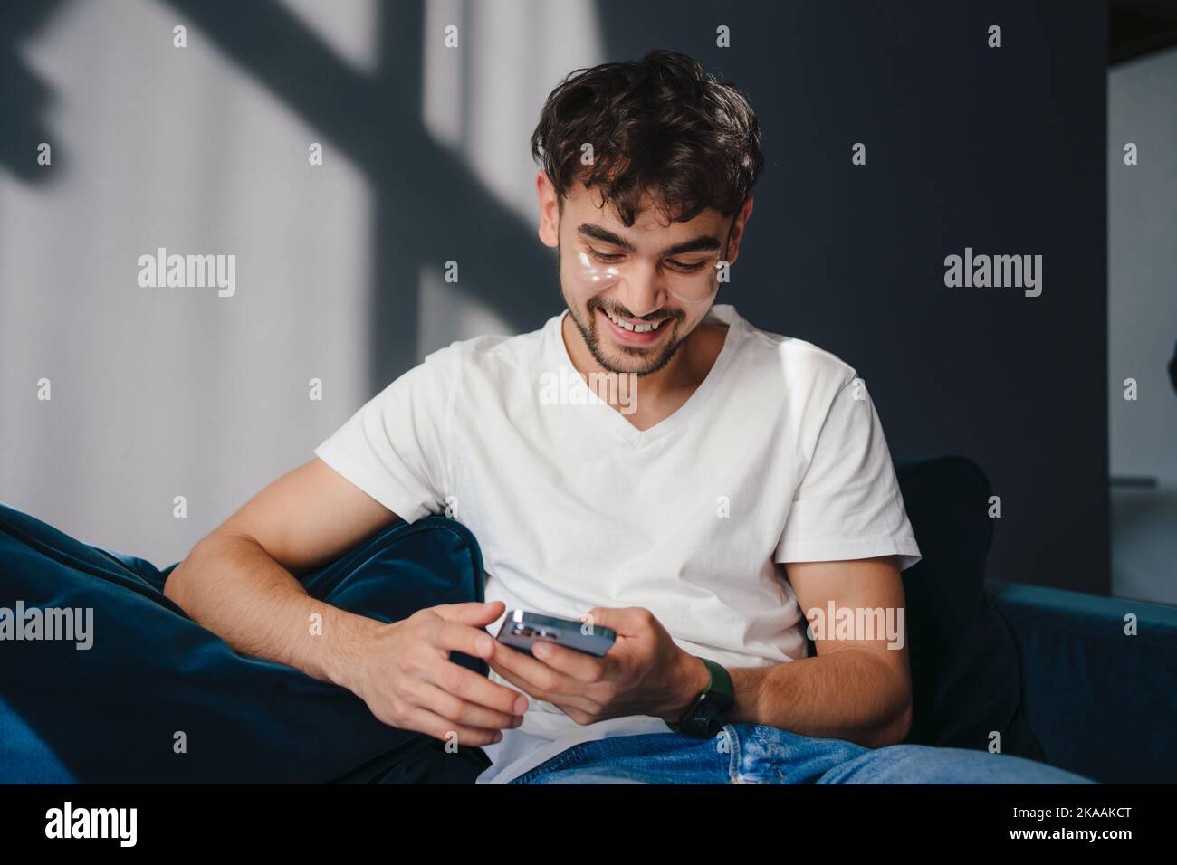 Attractive man with moisturizing patches under his eyes writing ...