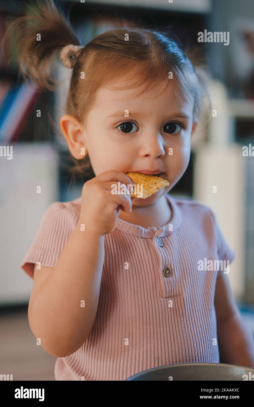 Portrait of a girl looking into the camera as she bites into her ...