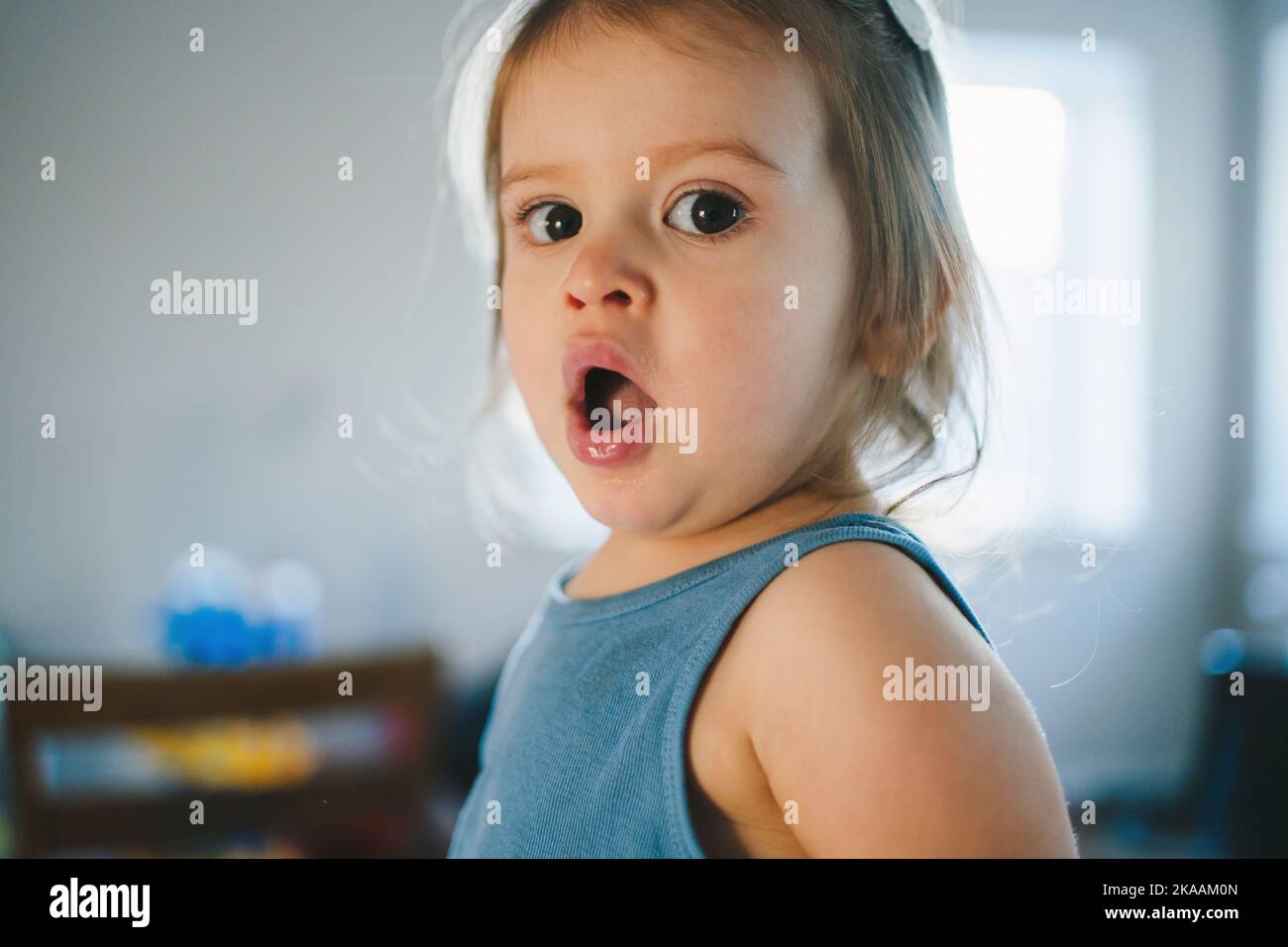 Portrait of a cute and tired baby girl yawning before bed time ...