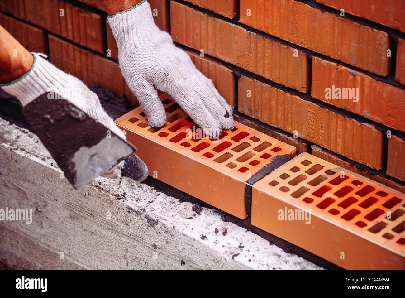 Builder laying bricks on construction site Stock Photo - Alamy