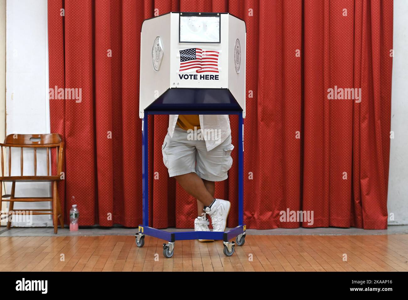 A man stands behind a voting privacy booth to fill out a ballot in ...