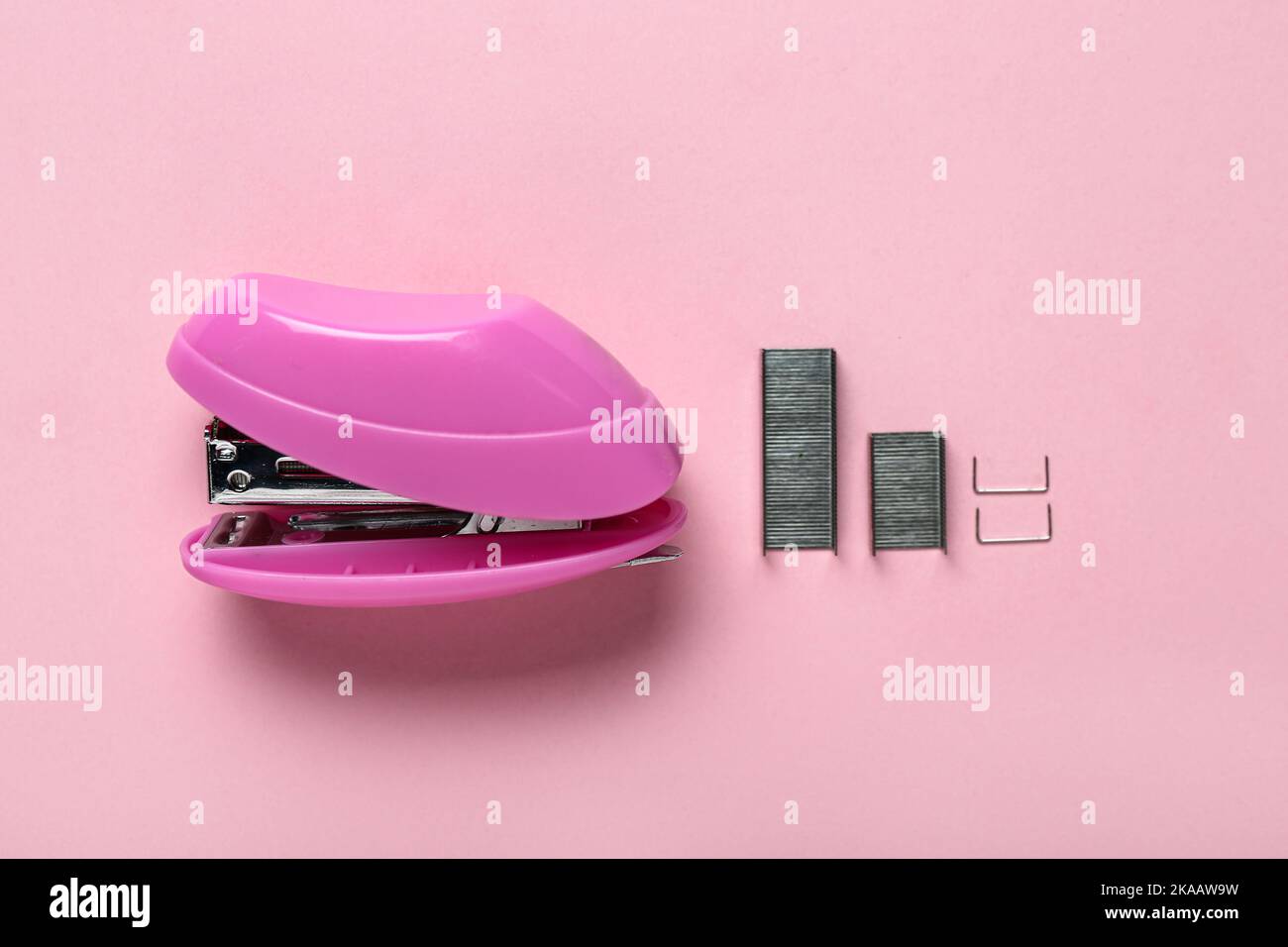 Office stapler and staples on pink background Stock Photo - Alamy