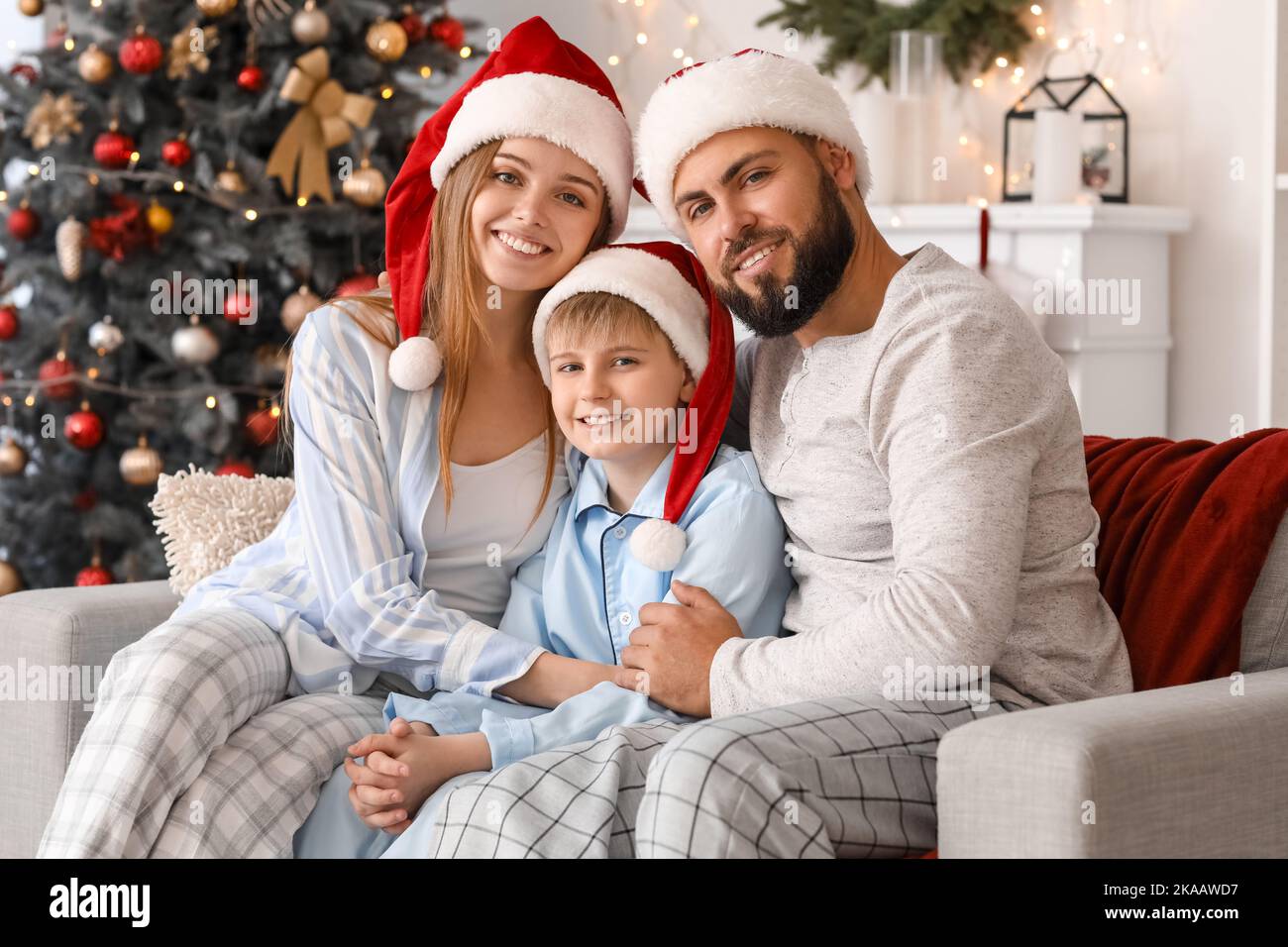 Happy parents with their little son in Santa hats sitting at home on ...