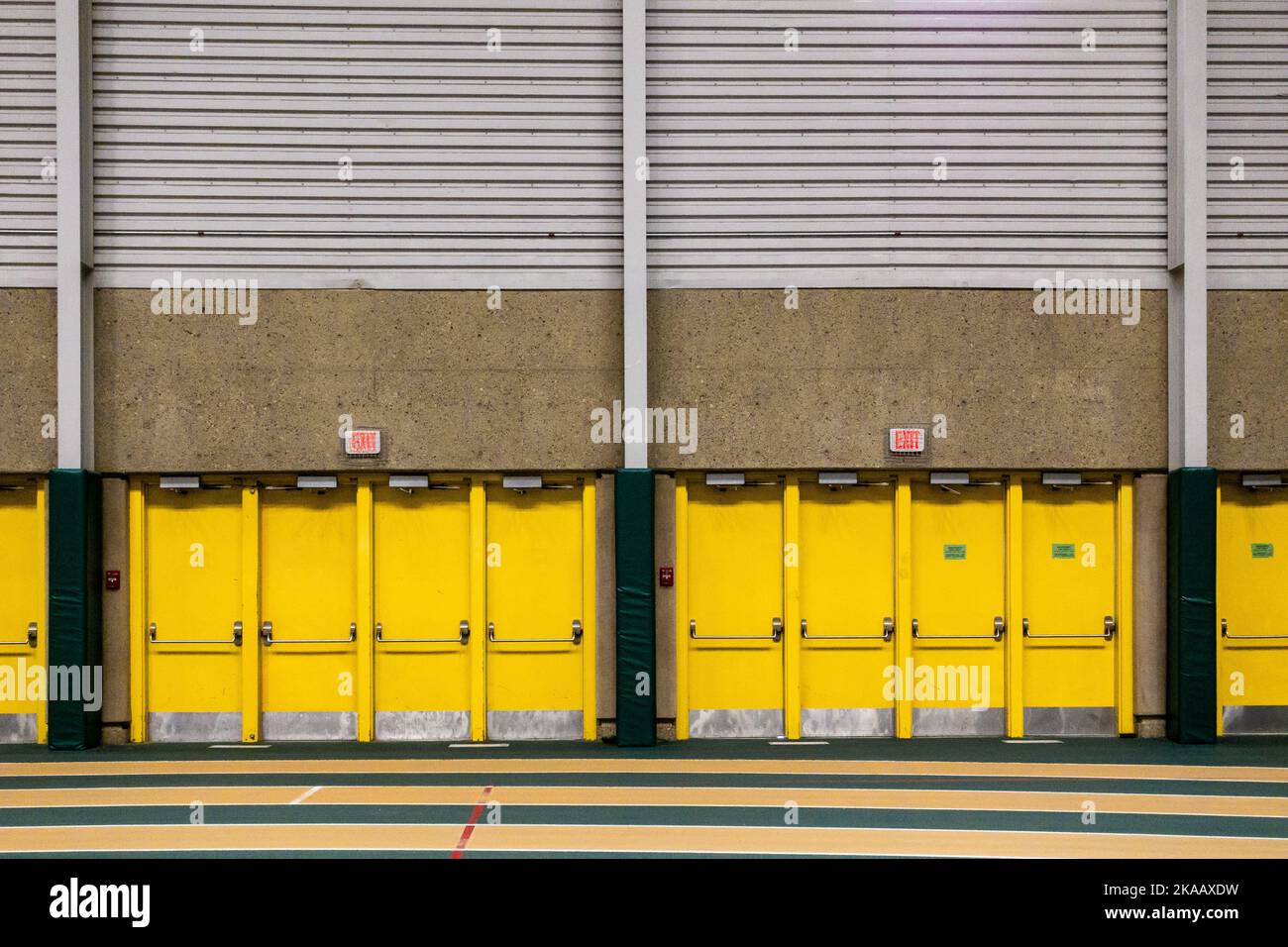 Row of yellow doors under exit signs inside a public sports arena Stock ...