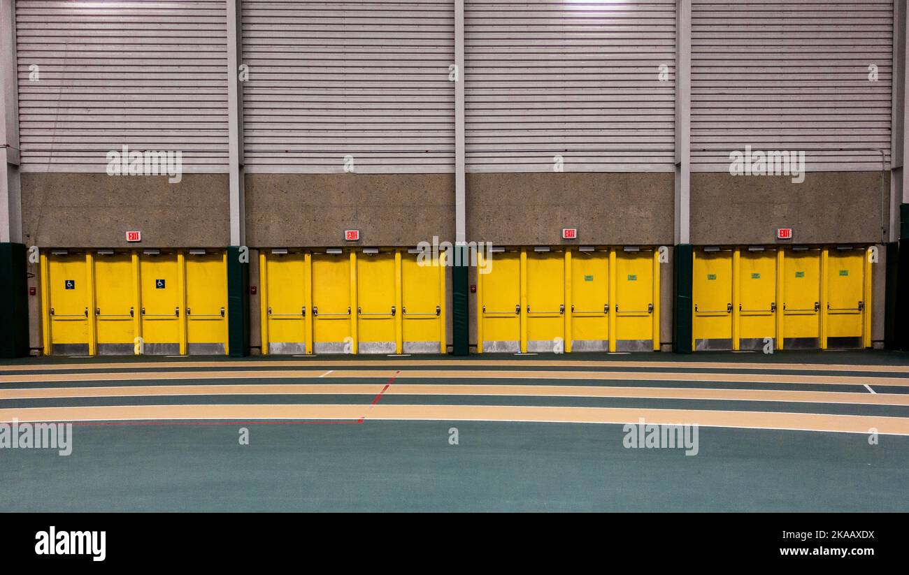 Row of yellow doors under exit signs inside a public sports arena Stock ...