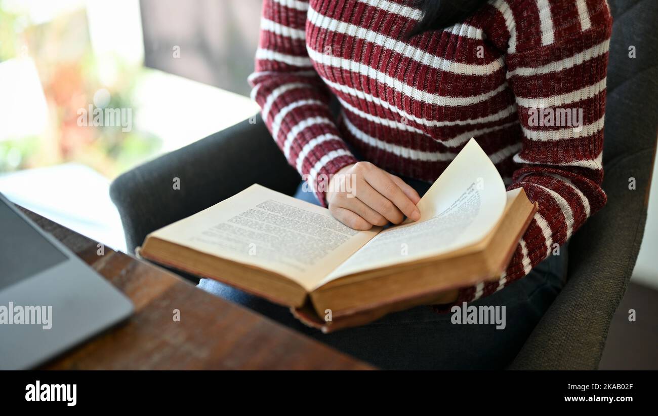 A smart young Asian female college student reading a book, researching ...