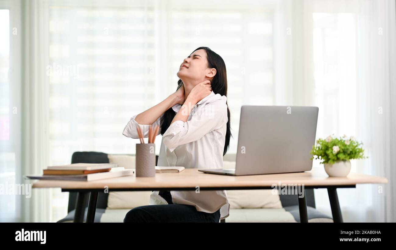 Overworked young Asian businesswoman or female office worker suffering ...