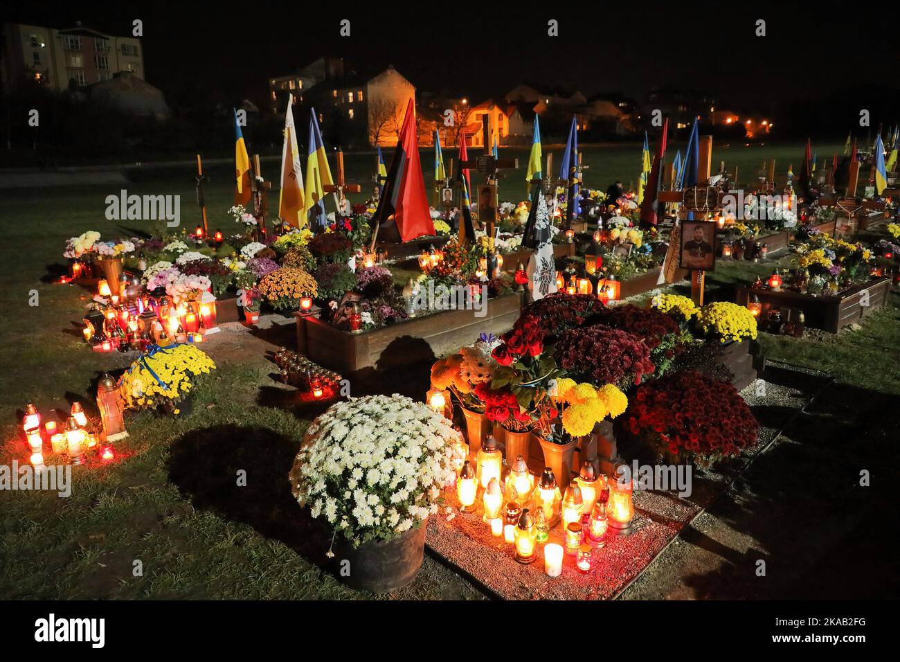 Lit candles, lamps, flowers, and flags seen at the graves of the ...