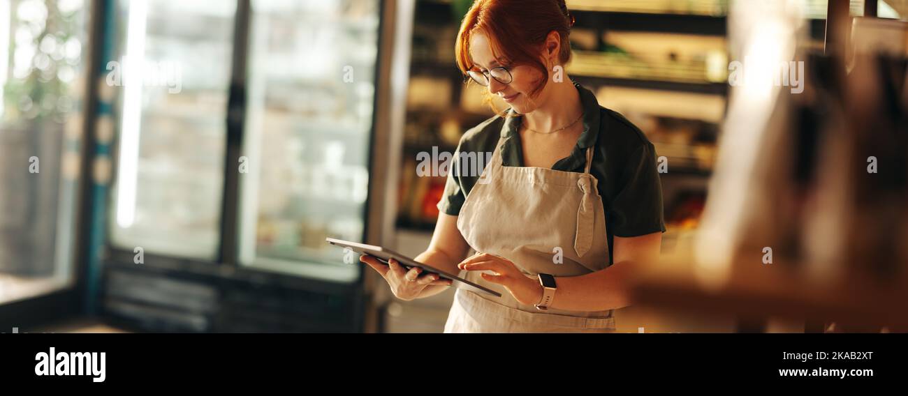 Happy supermarket owner using a digital tablet while standing in her ...