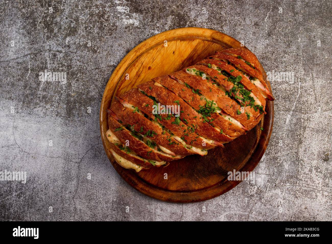 Cheese Stuffed Garlic Bread on a round wooden cutting board on a dark ...