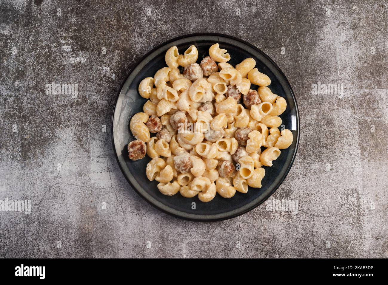Creamy Pasta with Meatballs on a round plate on a dark grey background ...