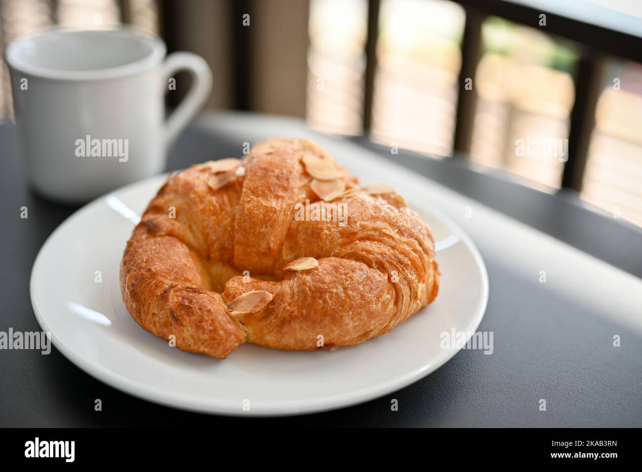 Delicious fresh French croissant with almond slice on a white plate ...